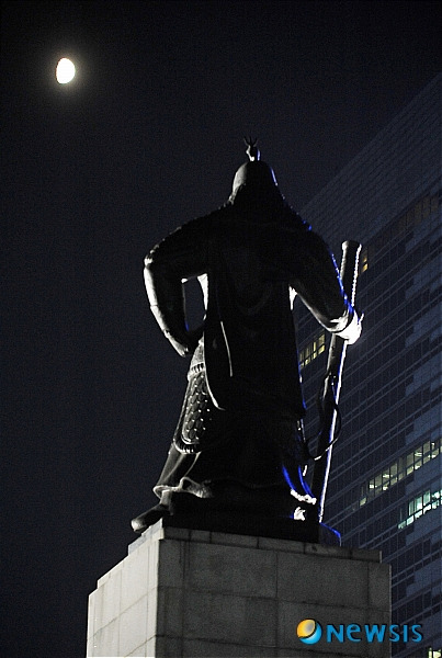 달빛 아래 실루엣으로 빛나는 이순신 장군 동상의 뒷모습